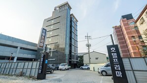 Um edifício com design arquitetônico moderno, destacando uma entrada imponente com sinalização.