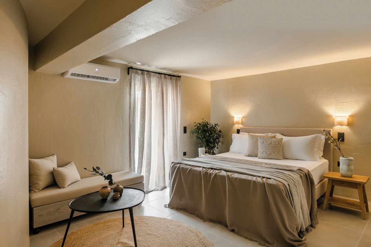 Quarto com cama, sofá, mesinha e abajur.