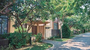 Rua residencial com casas, calçada e vegetação exuberante.