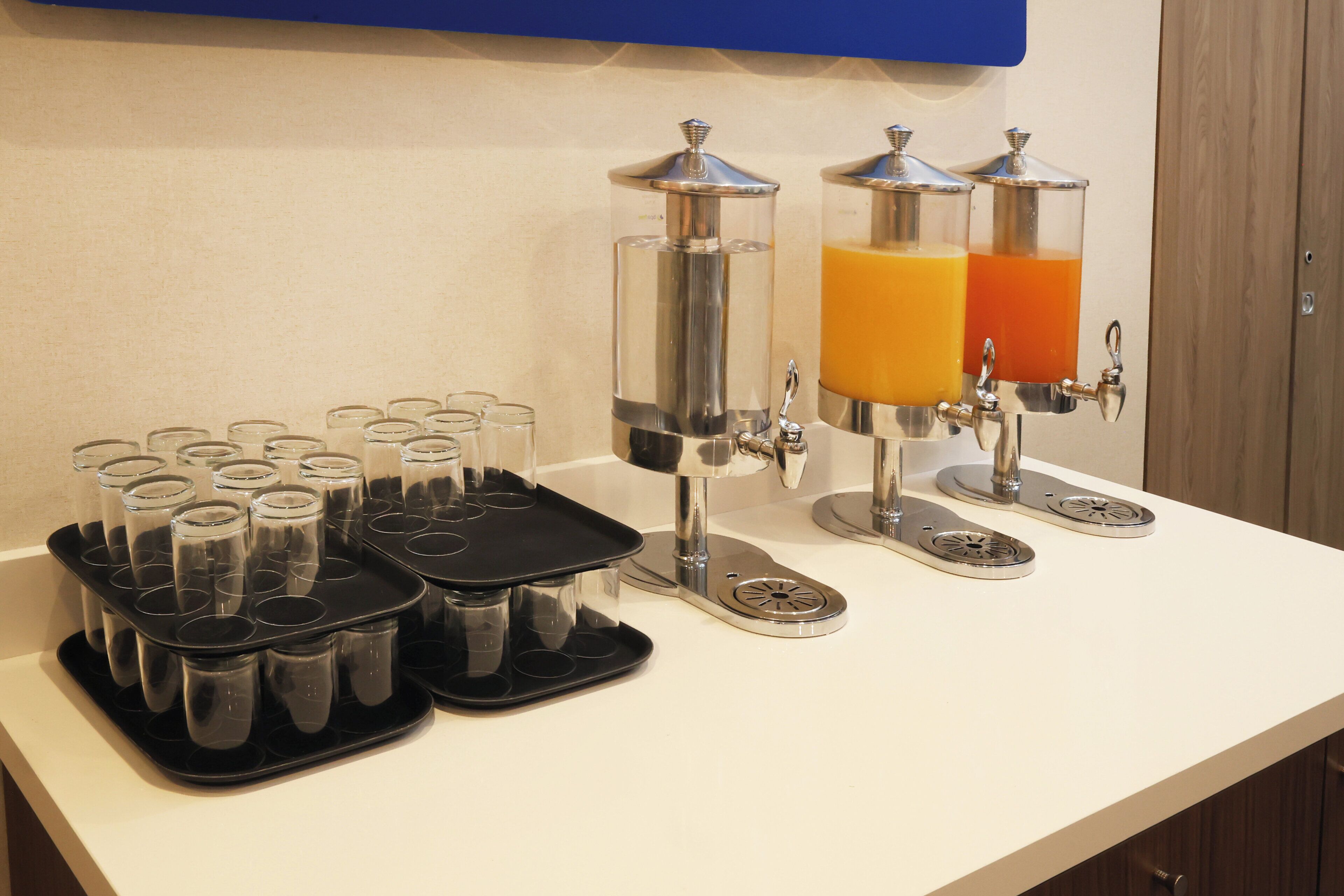 Uma estação de bebidas com dosadores e uma bandeja de copos.