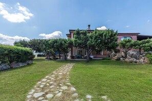 Uma casa com um caminho de pedras que leva a um pátio, cercado por vegetação e pedregulhos.