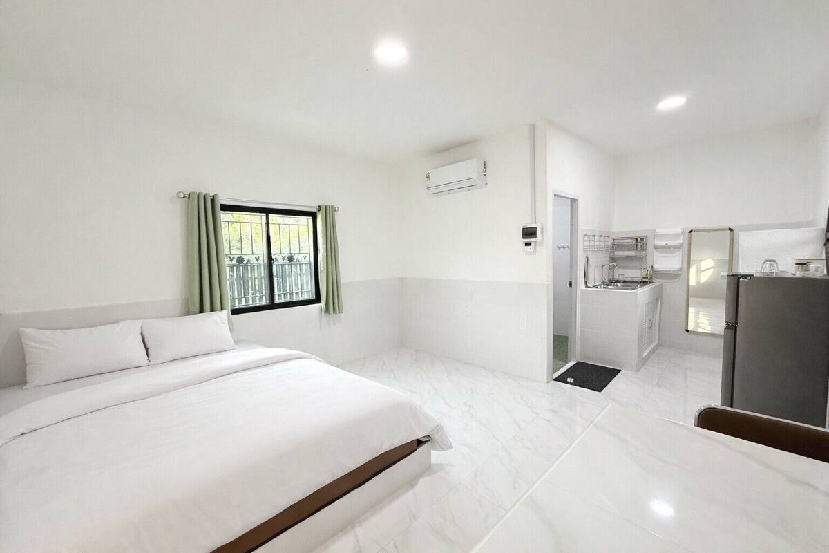 Quarto de hotel com cama, uma kitchenette pequena e um banheiro.