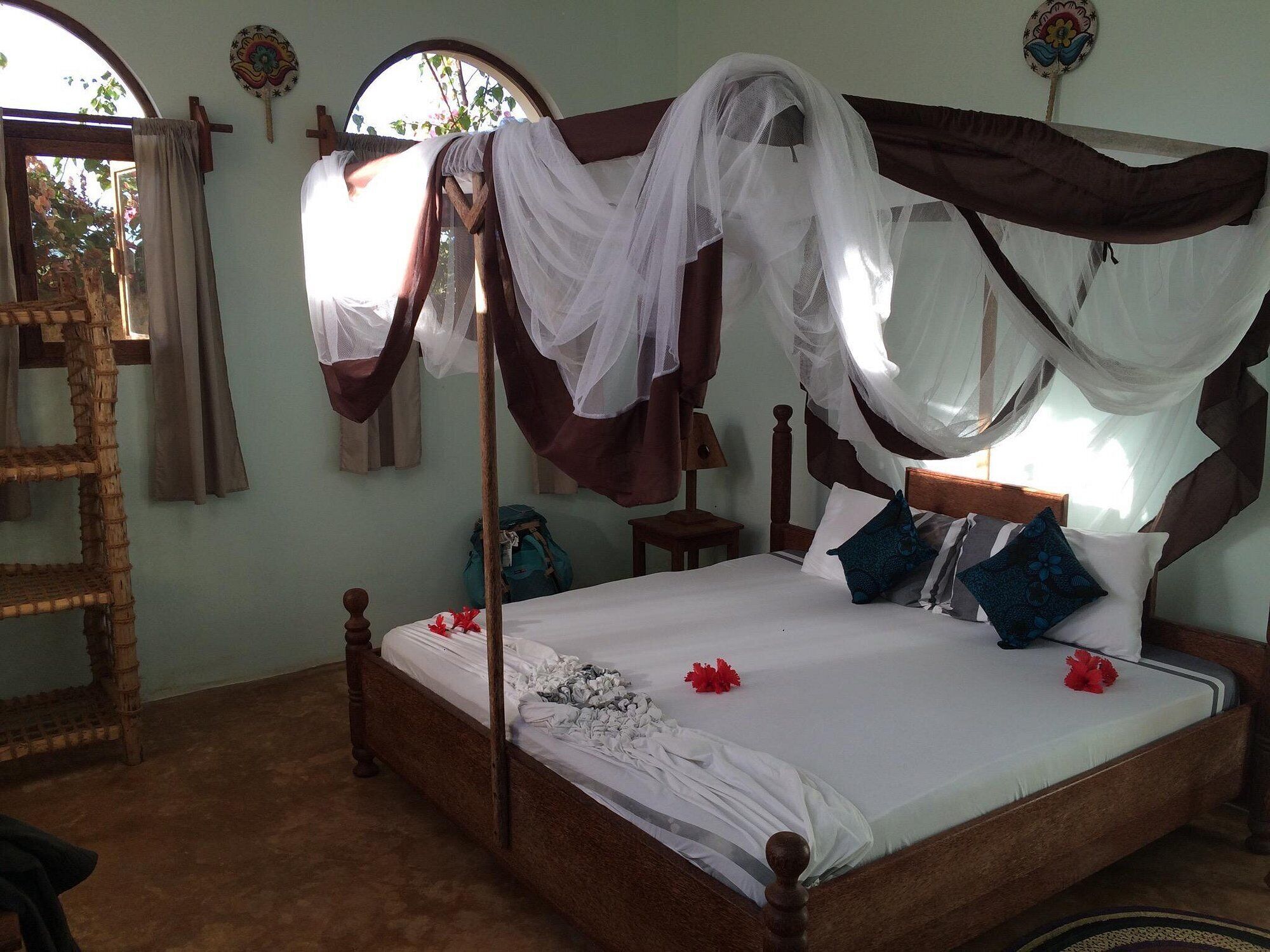 Uma cama com dossel, uma escada de madeira e uma pequena mesa.