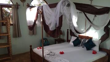 Uma cama com dossel, uma escada de madeira e uma pequena mesa.
