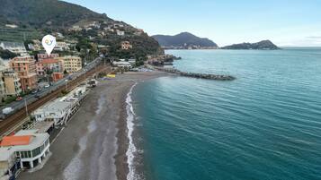 Uma cidade costeira com praia, edifícios e um afloramento rochoso no mar.