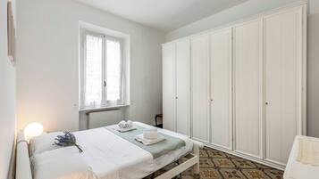 Quarto com cama, guarda-roupa, radiador e janela.