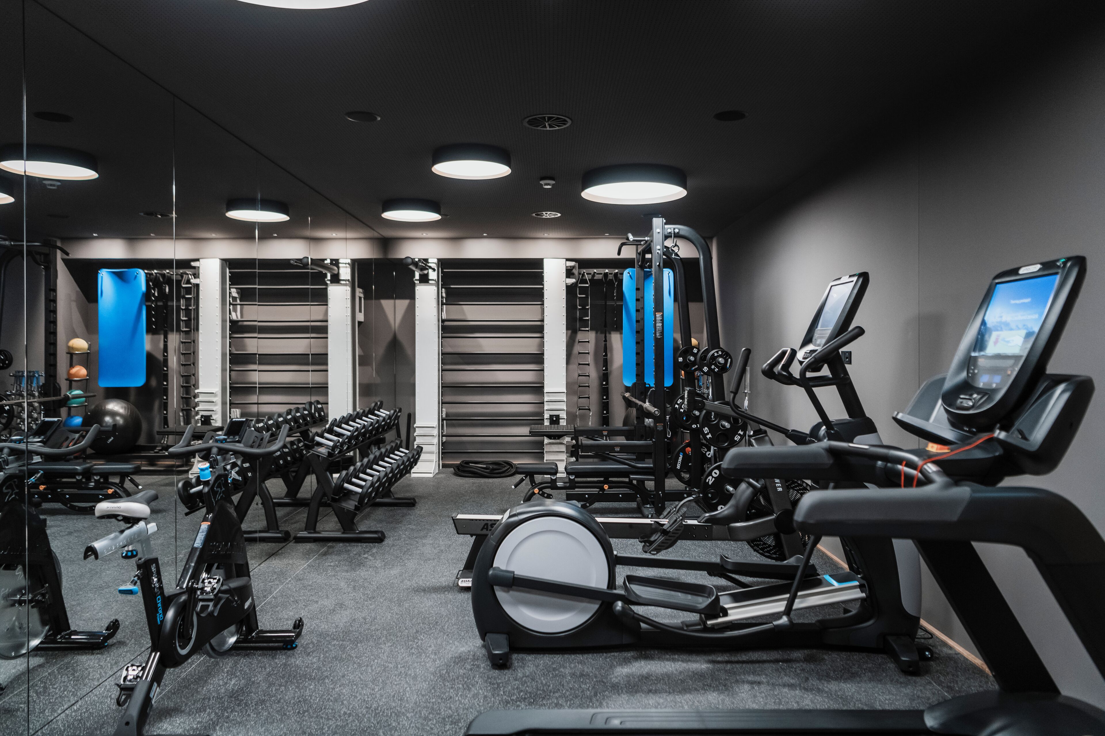 Uma academia com diversos equipamentos de exercício, incluindo esteiras, bicicletas ergométricas e máquinas de musculação.