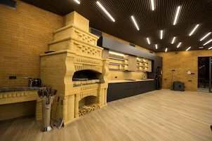 Uma cozinha moderna com forno de tijolos, piso de madeira e um espaço de bar integrado.