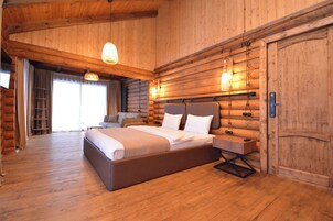 Quarto em estilo de cabana de tronco com uma cama grande, paredes de madeira e piso de madeira.