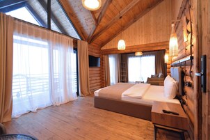 Um quarto no estilo de cabana de tronco com uma cama grande, pisos de madeira e uma varanda.