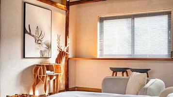 Quarto com cama, escrivaninha com cadeira, janela com persianas e um quadro de um veado na parede.