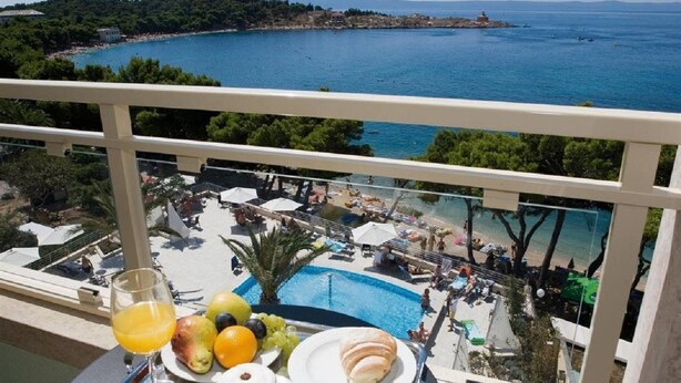 Varanda com mesa posta para o café da manhã, vista para a piscina e a praia.