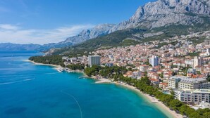 Uma cidade costeira com praia, edifícios e montanhas ao fundo.