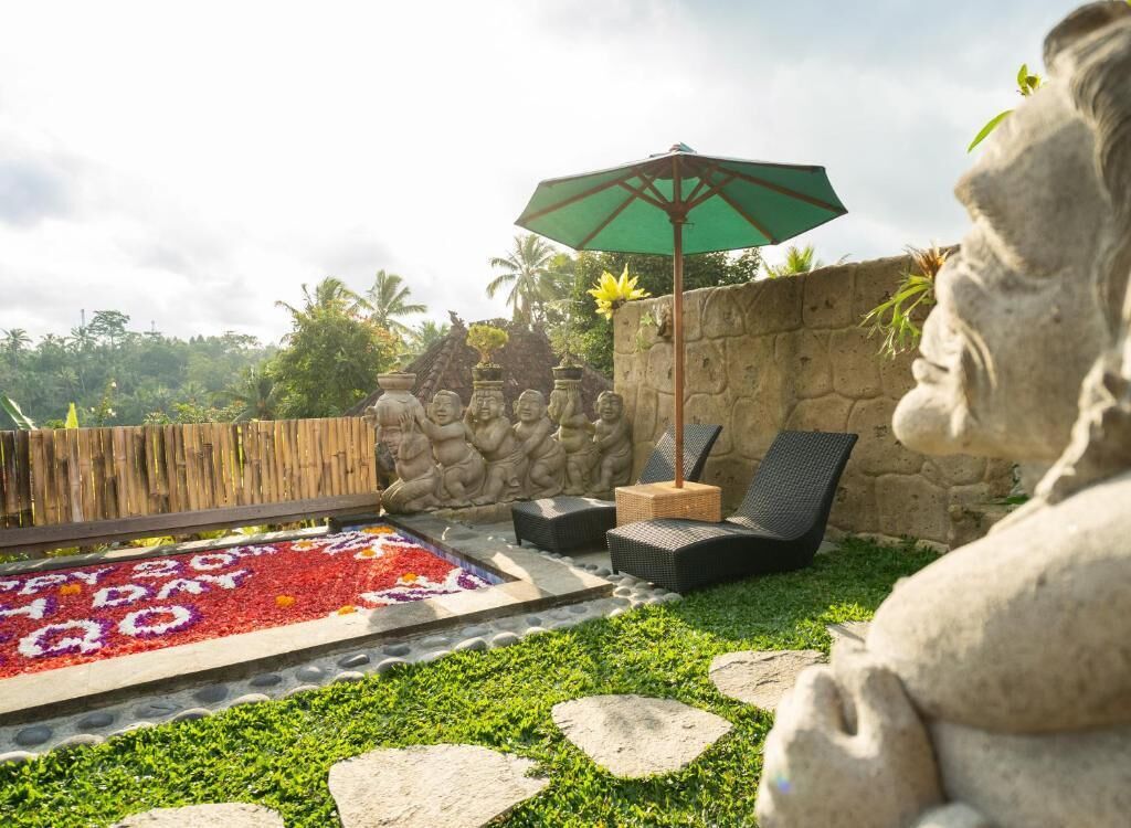 Uma estátua de pedra, um muro de pedra, um banco de pedra, um caminho de pedra, um vaso de pedra, uma mesa de pedra, uma cadeira de pedra, um guarda-sol de pedra e um canteiro de flores de pedra, além de uma piscina de pedra.