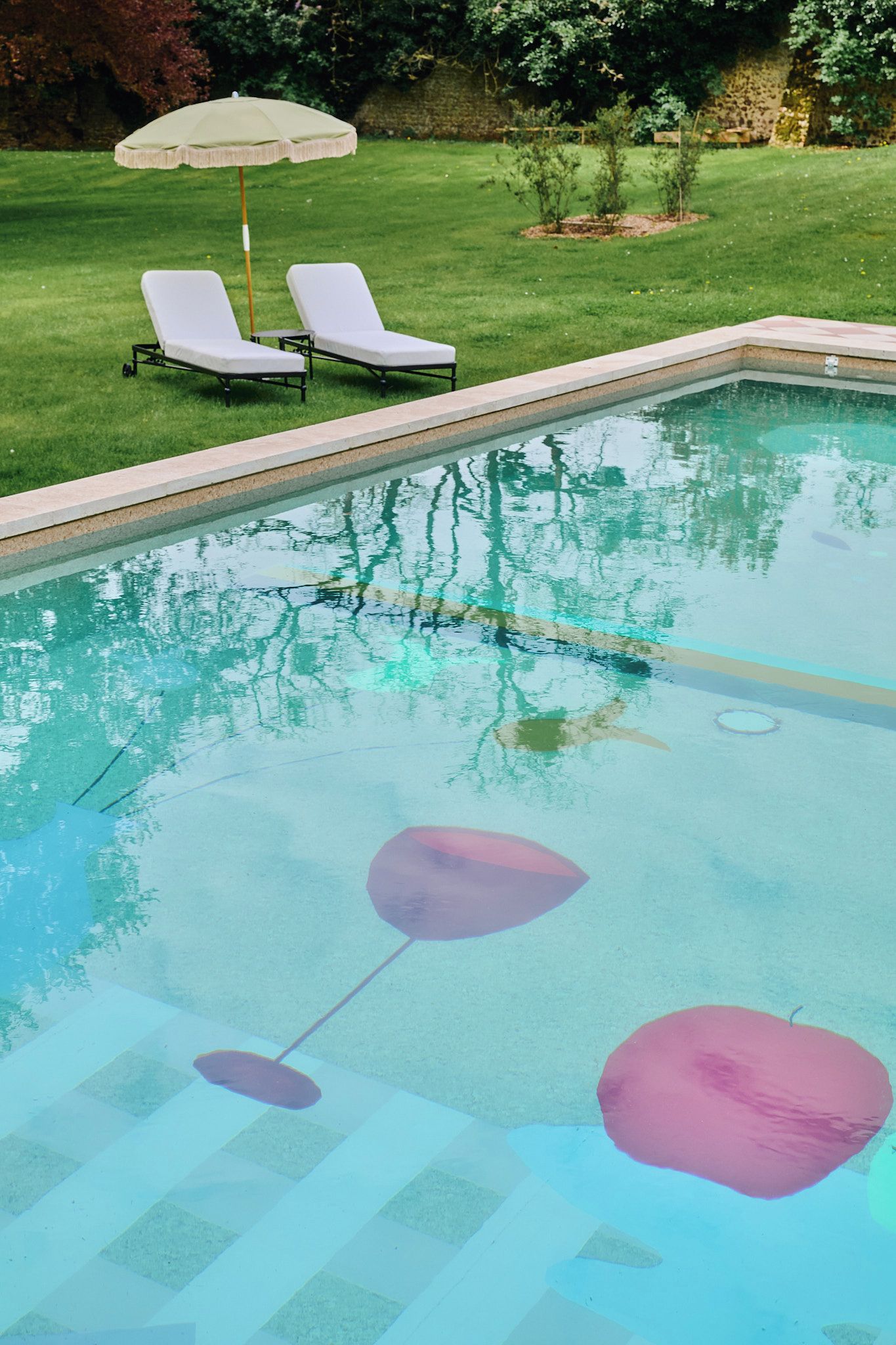 Piscina com duas espreguiçadeiras e um guarda-sol.