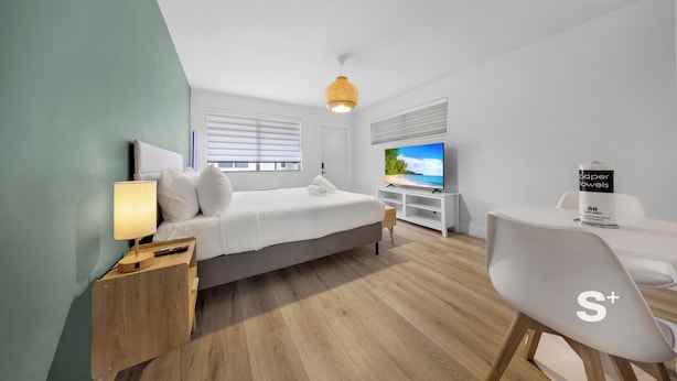 Quarto de hotel moderno com cama, televisão, escrivaninha e cadeira.