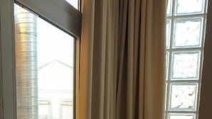 Quarto com porta de correr de vidro que dá para área externa com um pátio ladrilhado e vista de um edifício.