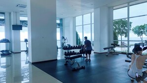 Uma academia com equipamentos de ginástica, amplas janelas e vista para o exterior.