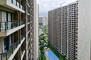 Um edifício residencial alto com várias varandas, piscina e área ajardinada.
