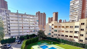 Zona residencial com piscina, cercada por gramados bem cuidados e edifícios altos.