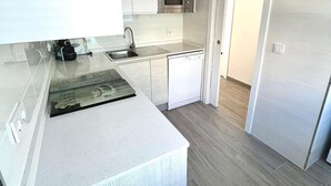 Cozinha moderna com armários brancos, micro-ondas de aço inoxidável e máquina de lavar louça.