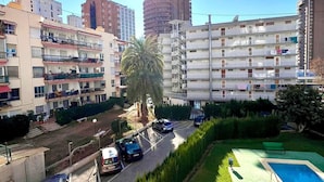 Um edifício residencial com várias varandas, piscina e uma palmeira.