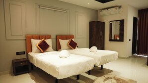 Quarto de hotel com duas camas, mesa de cabeceira, espelho e armário.
