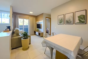 Quarto moderno com uma mesa de jantar, um sofá, uma planta em vaso e obras de arte na parede.
