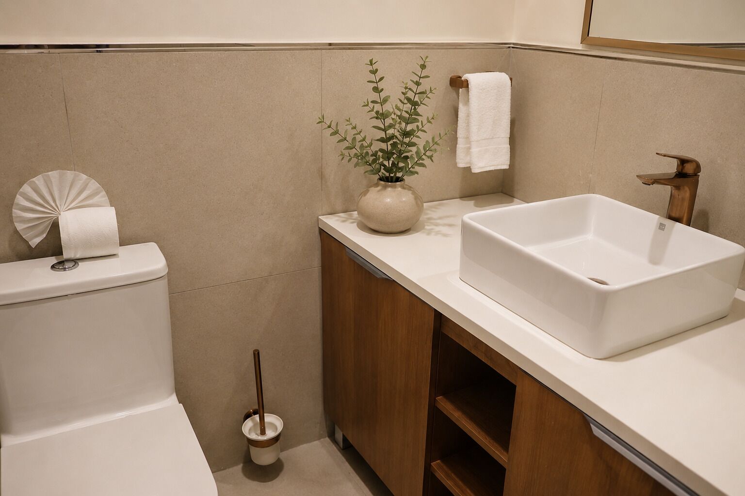 Um banheiro com vaso sanitário, pia, vaso com planta e toalha pendurada na parede.