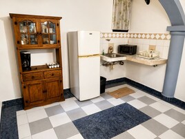 Uma cozinha com armário de madeira, geladeira branca, micro-ondas e pia.