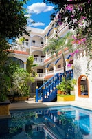 Uma área de piscina com escadaria azul, várias varandas e vegetação exuberante.