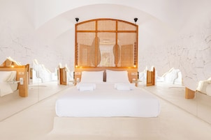 Quarto de hotel moderno com uma cama grande, uma cabeceira original e uma janela ampla.