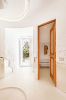 Um interior claro e branco, com uma porta de madeira que dá para uma escadaria.