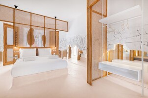 Quarto de hotel moderno com uma cama grande, um painel de madeira e uma mesa de consola branca.