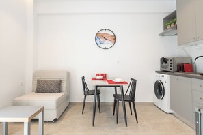 Um espaço compacto com mesa de jantar, cadeiras, sofá, máquina de lavar e micro-ondas.