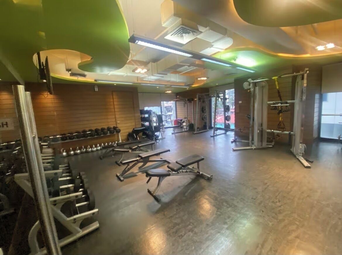 Uma academia com equipamentos de musculação, bancos e diversos aparelhos.