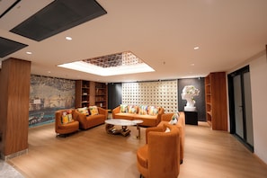 Um hall moderno com pé-direito alto, área de estar central com sofás e poltronas, uma mesa de centro e uma escultura decorativa.