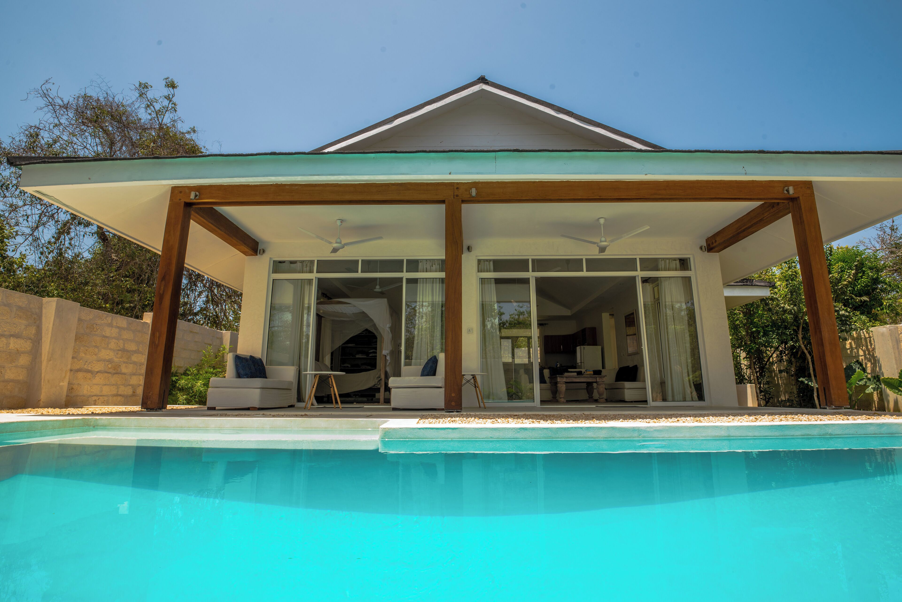 Uma casa moderna com piscina, varanda coberta e porta de vidro que dá para uma sala de estar.