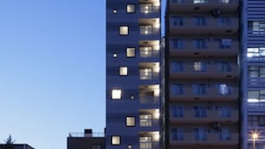 Um edifício com vários andares e janelas iluminadas, provavelmente um conjunto habitacional.
