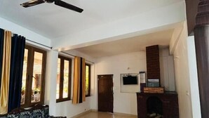 Uma sala de estar espaçosa com ventilador de teto, um sofá, uma mesa de jantar e uma lareira.