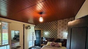 Quarto com uma cama, uma escrivaninha e uma cadeira. Há uma janela e uma porta que dá para outro cômodo.