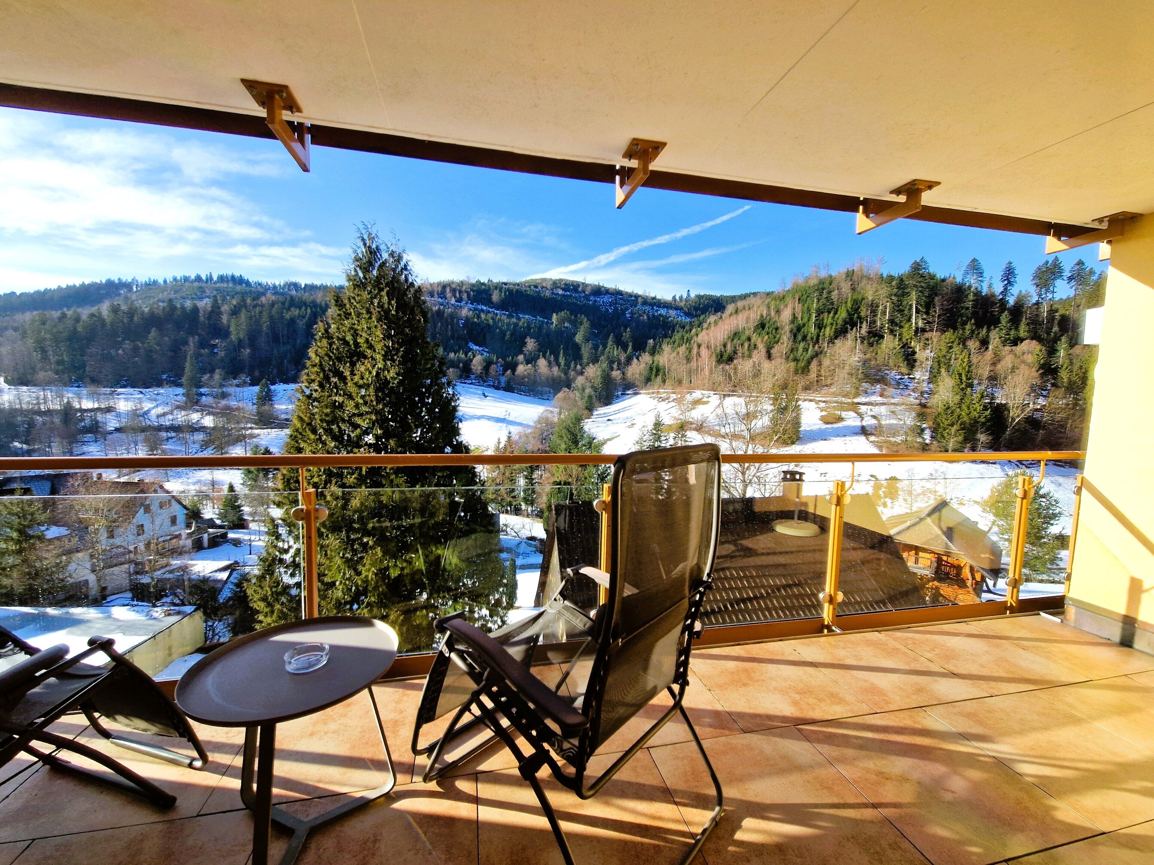 Uma varanda com vista para uma paisagem nevada e um prédio ao longe.