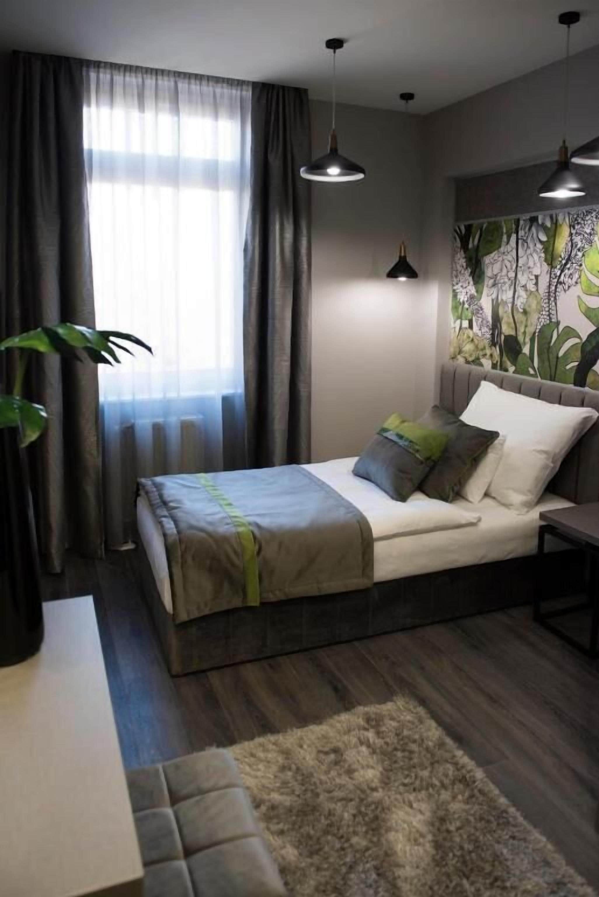 Um quarto moderno com cama, mesa de cabeceira e uma janela grande com cortinas.