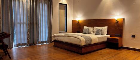 Quarto moderno com cama grande, cabeceira de madeira e mesa de cabeceira.