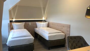Quarto com duas camas, uma cadeira e uma mesa.