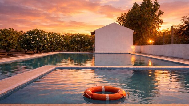 Piscina com boia salva-vidas, rodeada por árvores e um edifício.