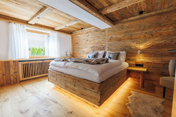 Quarto de cabana de madeira com cama, janela e radiador.