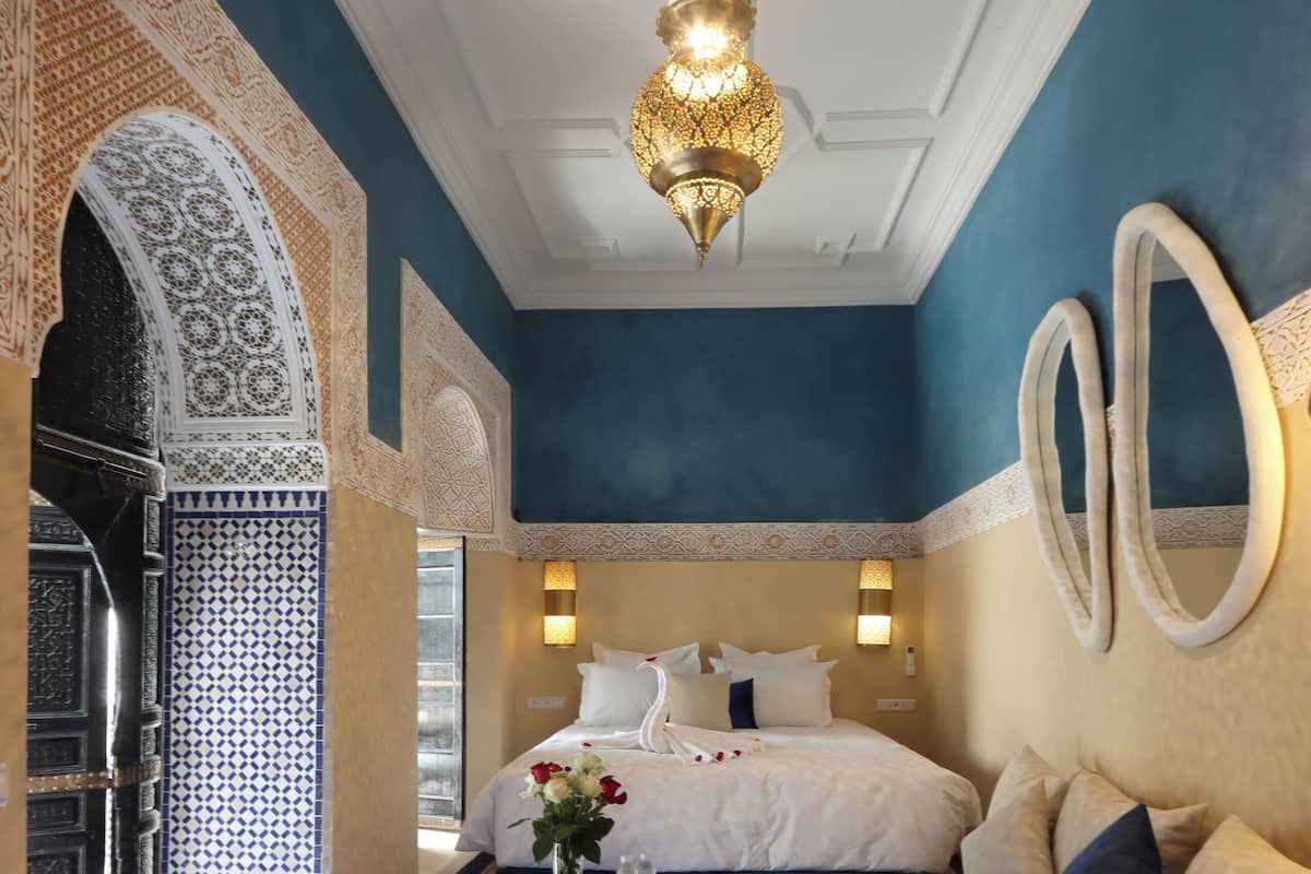 Quarto com cama, sofá, mesa de centro e lustre.