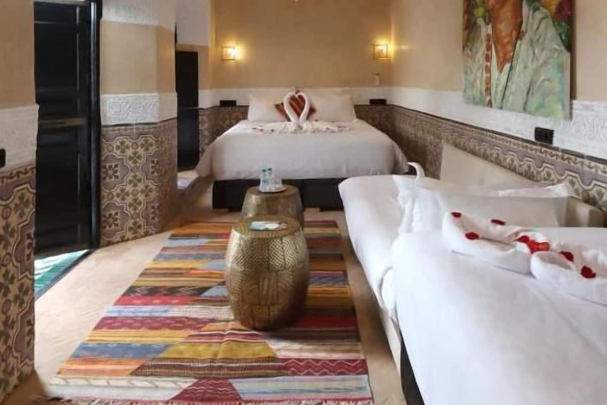 Quarto de hotel com cama, um vaso decorativo, pintura na parede e luminária no teto.