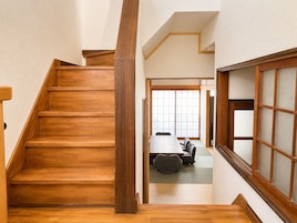 Escada de madeira que leva a um quarto com tatames, uma mesa baixa e um sofá.